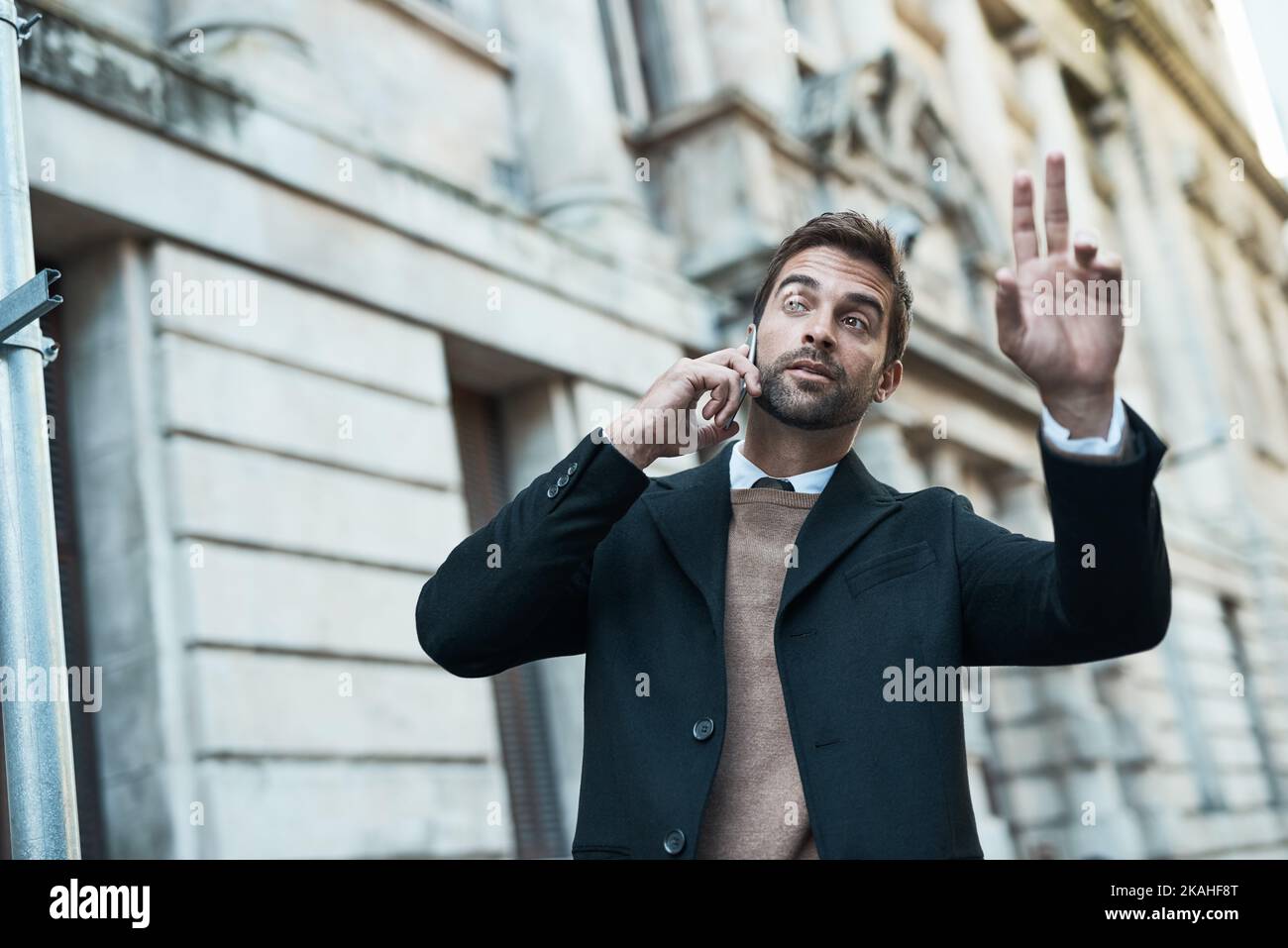 Taxi. a handsome businessman hailing a cab while making a phonecall ...