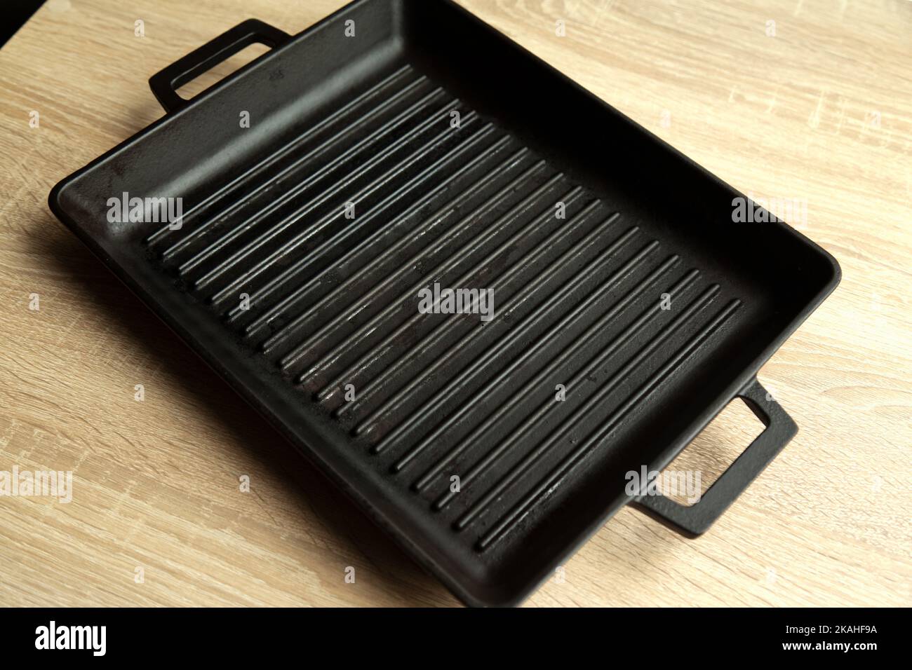 Empty black cast heavy iron grill pan on modern oak kitchen countertop ...