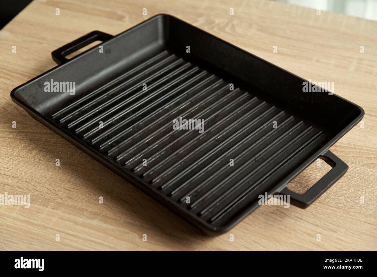 Empty black cast heavy iron grill pan on modern oak kitchen countertop ...