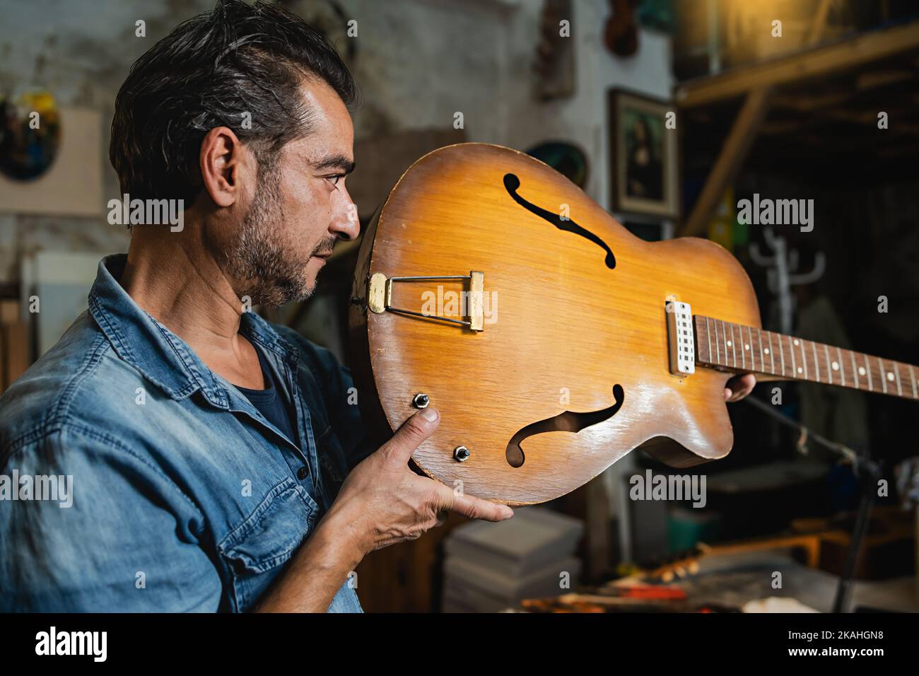 A luthier checks an hollow body guitar neck in his workshop to verify ...
