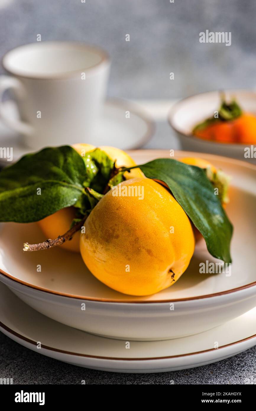 Close-up of persimmon fruits and an empty coffee cup Stock Photo - Alamy