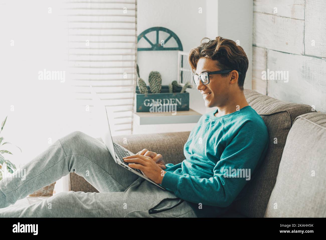 Happy teenager at home using laptop sitting comfortably on the sofa ...