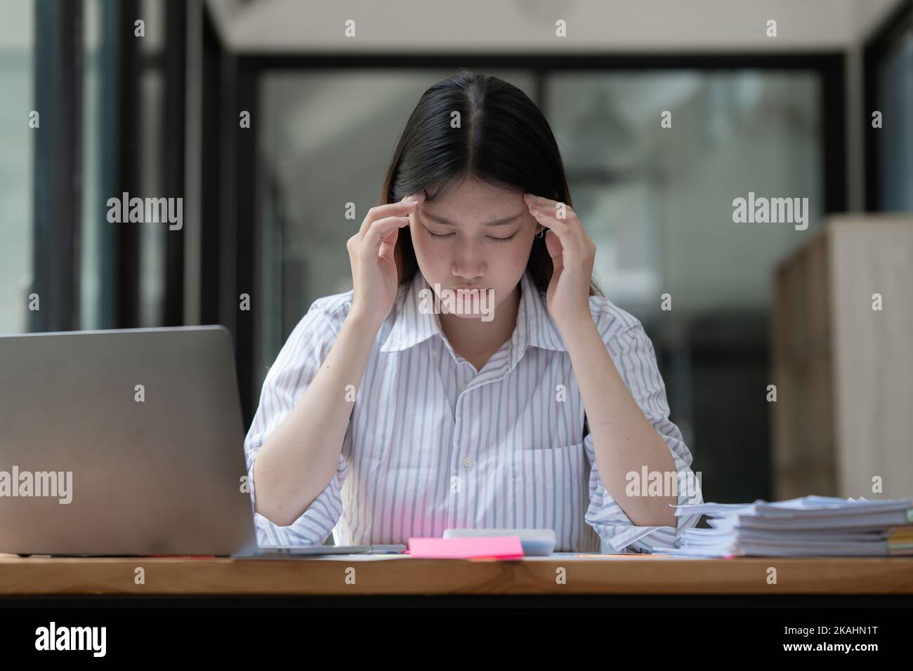 Stressed Asian business woman worry with many document on desk at ...