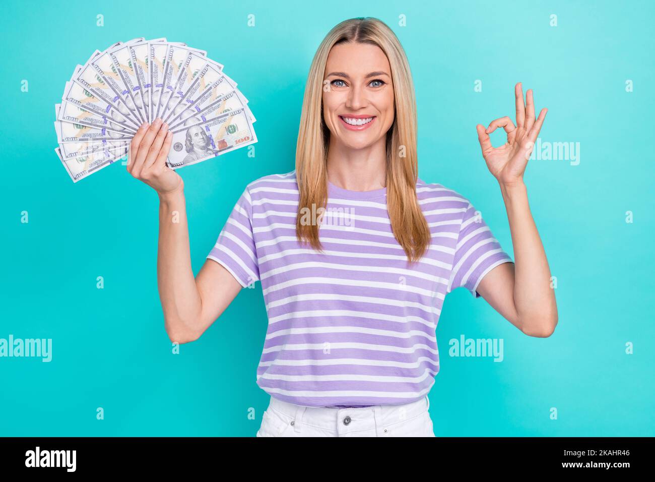 Photo of shiny beautiful confident woman blonde hair smiling hold money showing okey sign good ...