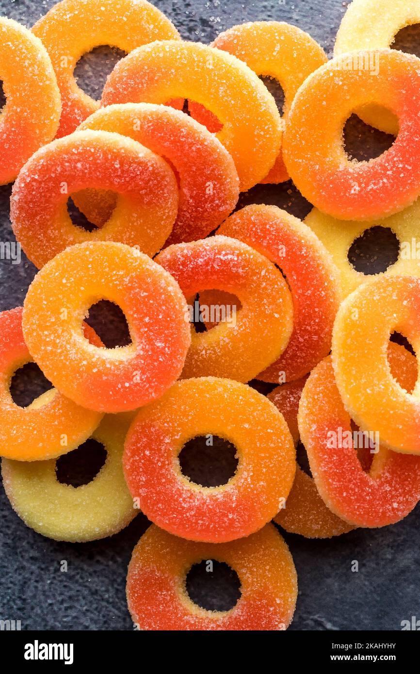 A pile of brightly coloured peach flavoured sugar coated gummy rings ...