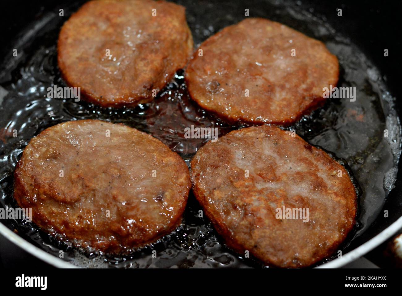 A close-up of 4 pieces of spicy fried beef burger cooked in a boiling ...