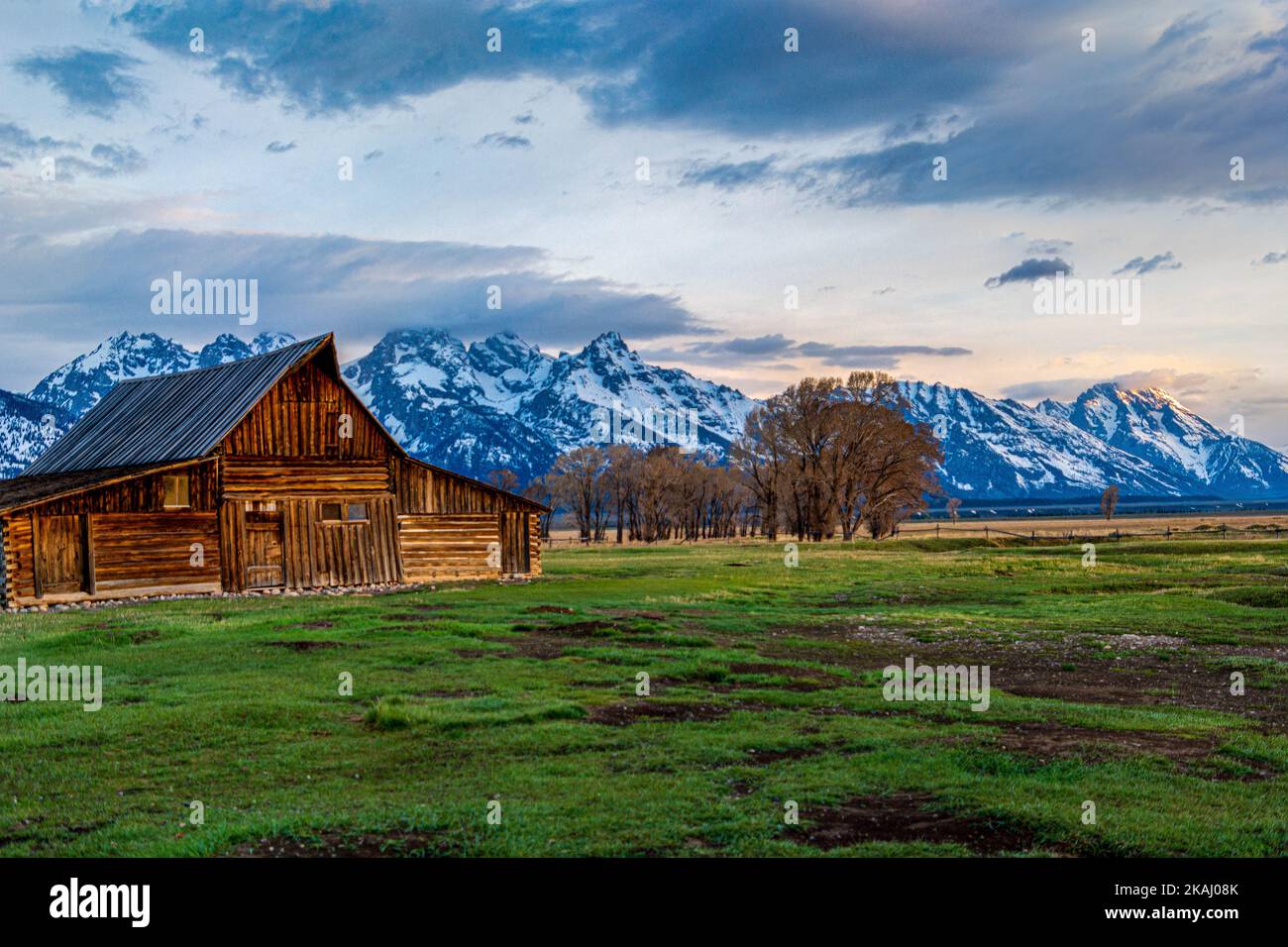 An artwork of a Grand Teton National with blue and white clouds, a hut ...