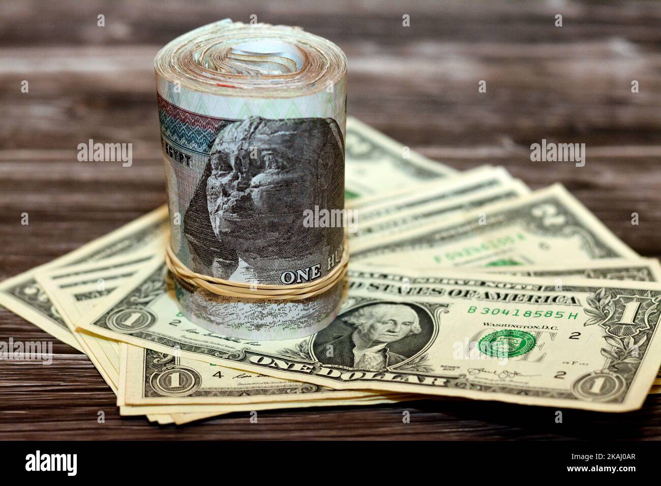 Egyptian money roll of 100 LE and pile of American money isolated on ...