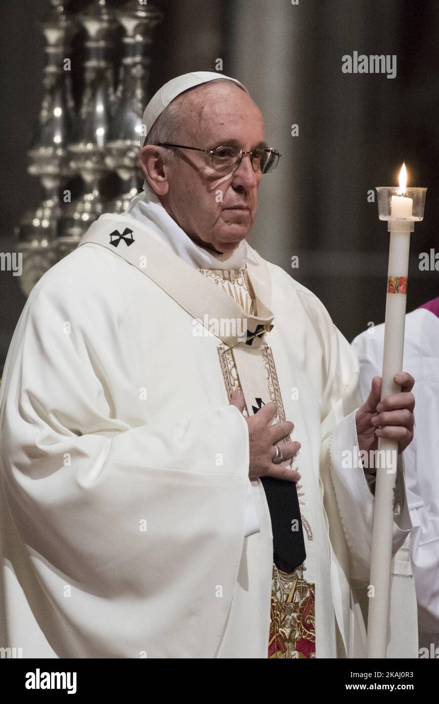 Pope Francis holds a candle as he celebrates a mass for nuns and priest ...