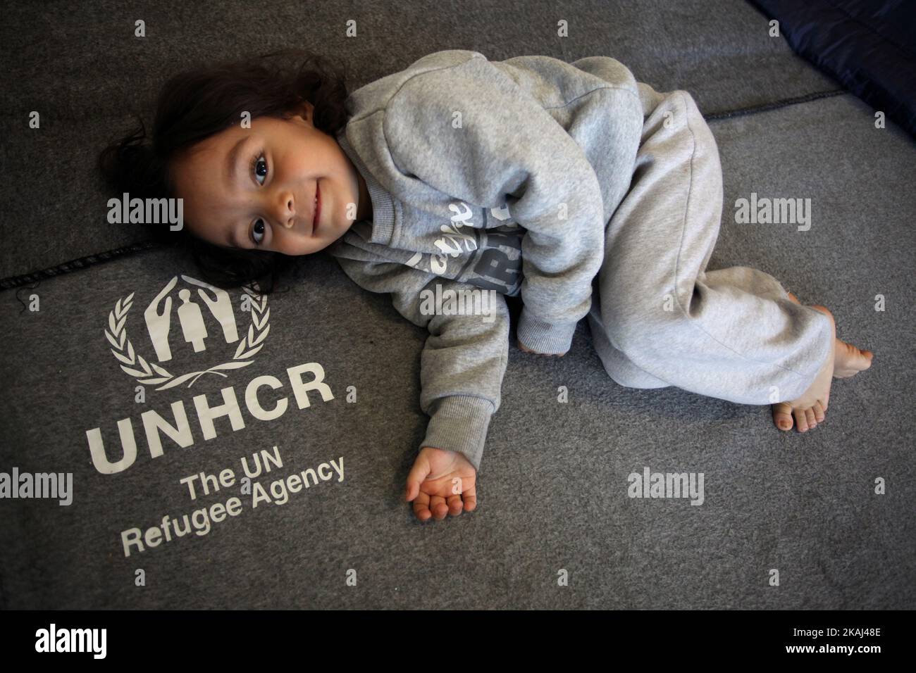 A girl is lying on a UNHCR blanket. Refugees and immigrants find ...