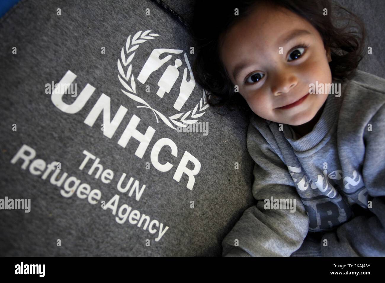 A girl is lying on a UNHCR blanket. Refugees and immigrants find ...