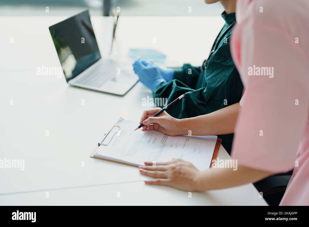 Asian doctors and nurses using computers and documents to view patient ...