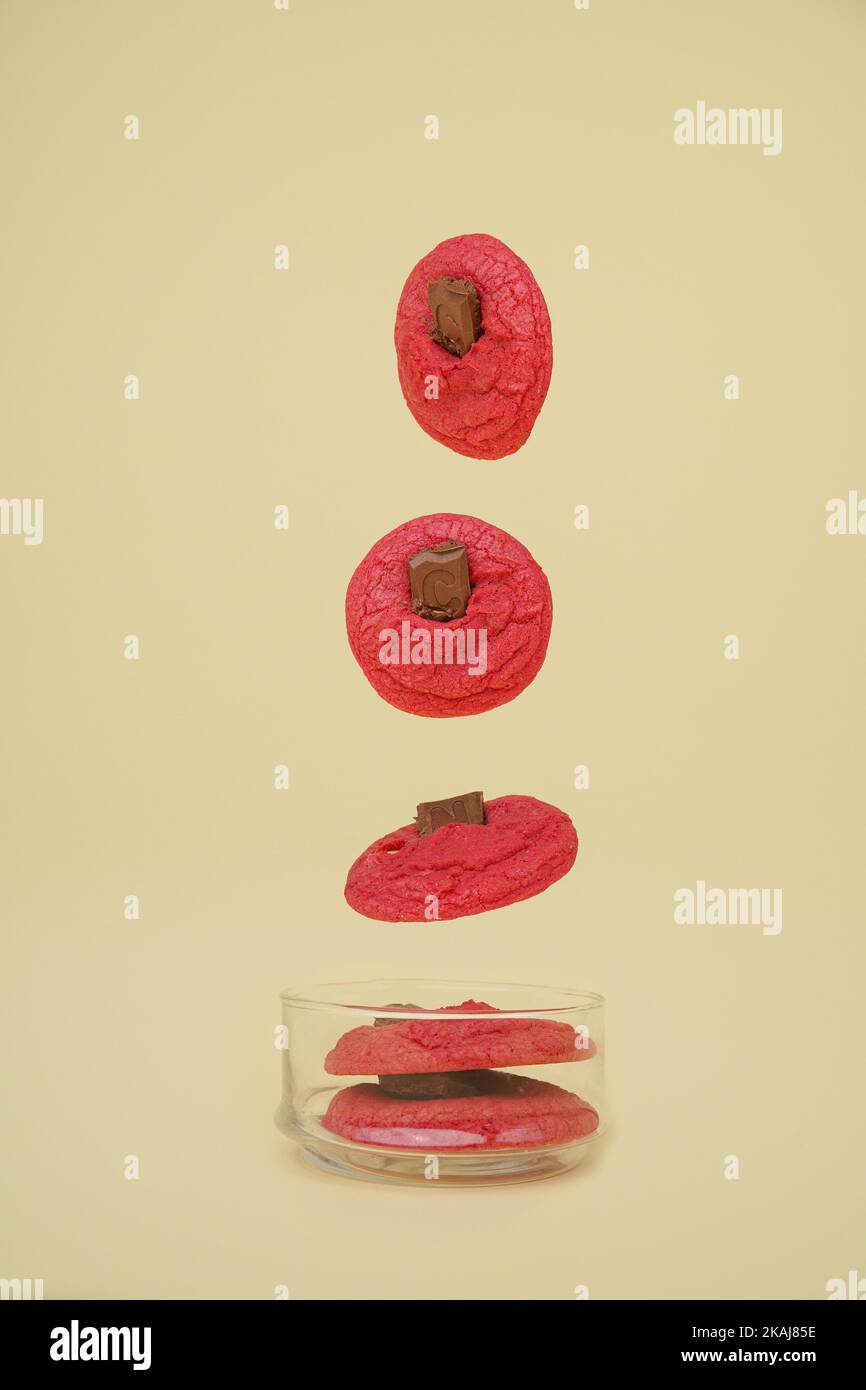 The pink cookies with chocolate falling in a transparent jar, vertical ...
