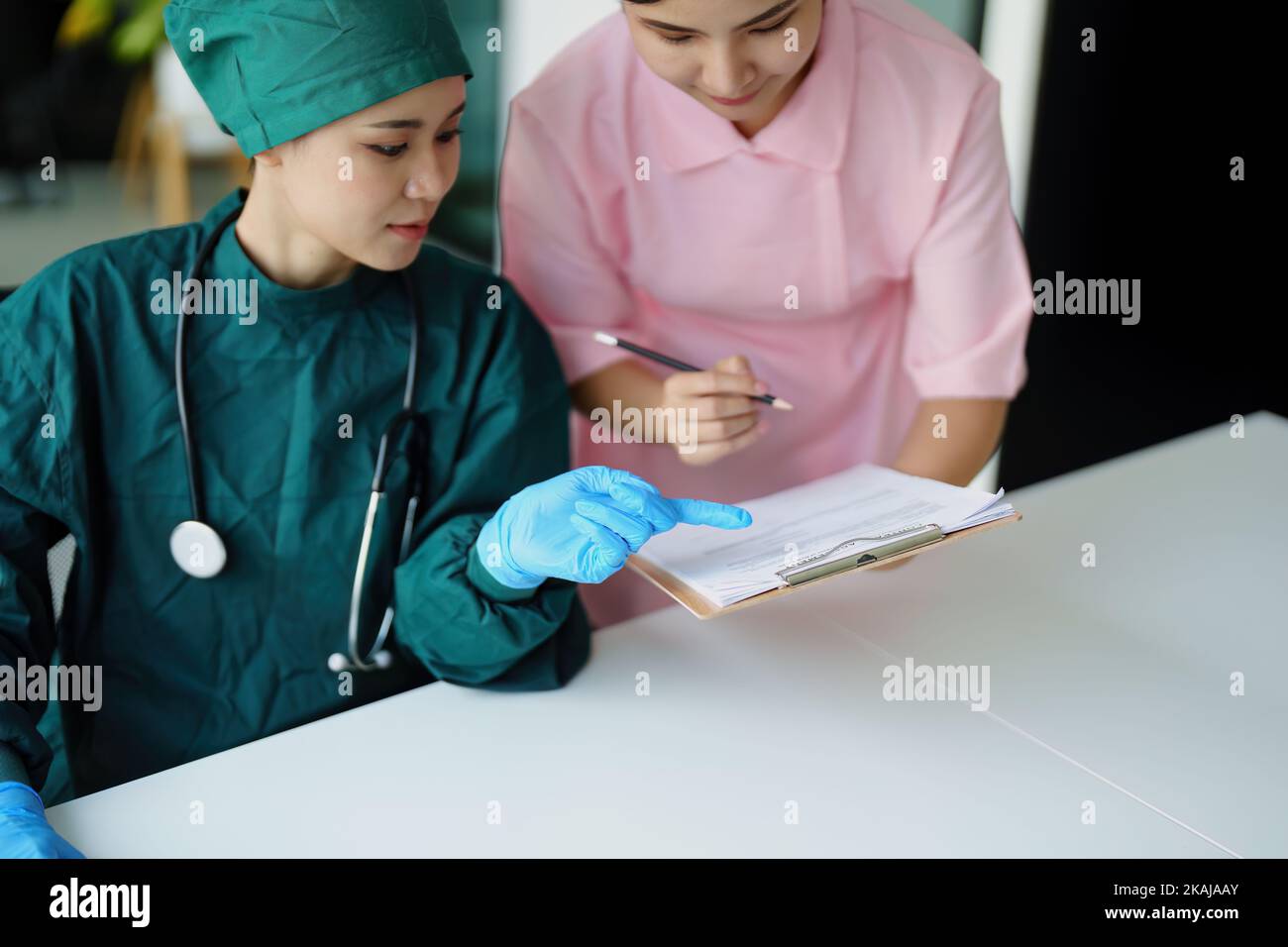 Asian doctors and nurses using computers and documents to view patient ...