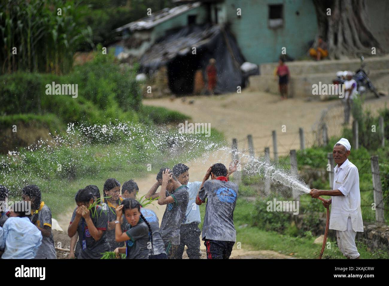 A farmer spreads water towards young kids, who came to enjoy Rice ...