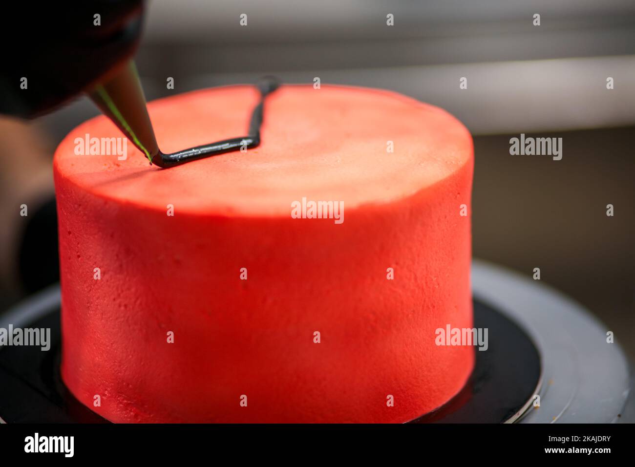 topping a red cake with black dark chocolate icing Stock Photo - Alamy