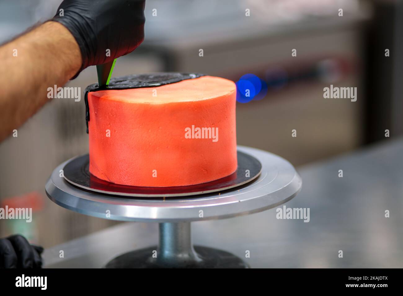 topping a red cake with black dark chocolate icing Stock Photo - Alamy
