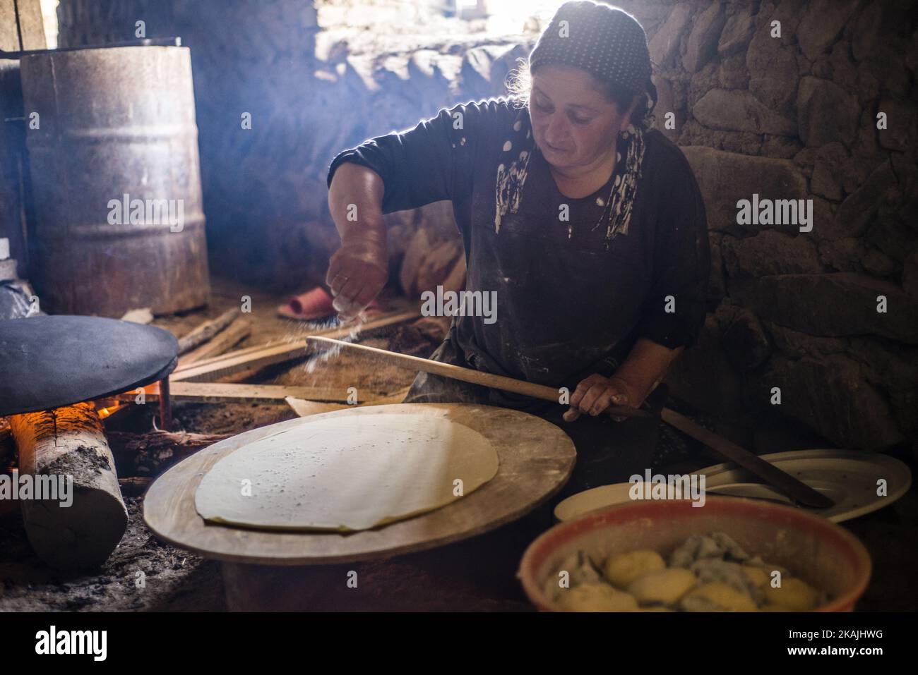 A woman makes bread in the kitchen of her house in Khinalig village ...