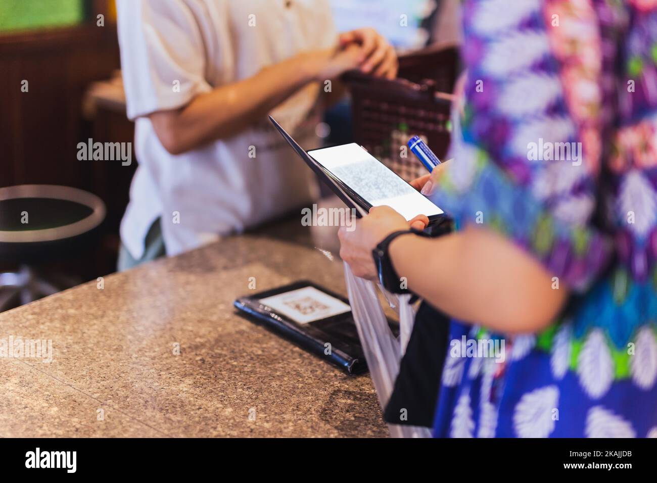 Woman customer scanning QR code payment via mobile phone at cashier ...