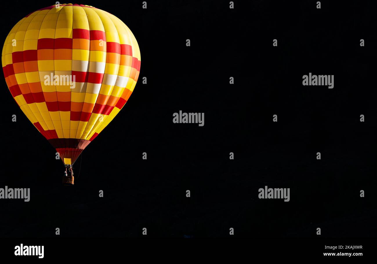 A large orange red yellow hot air balloon isolated on a black ...
