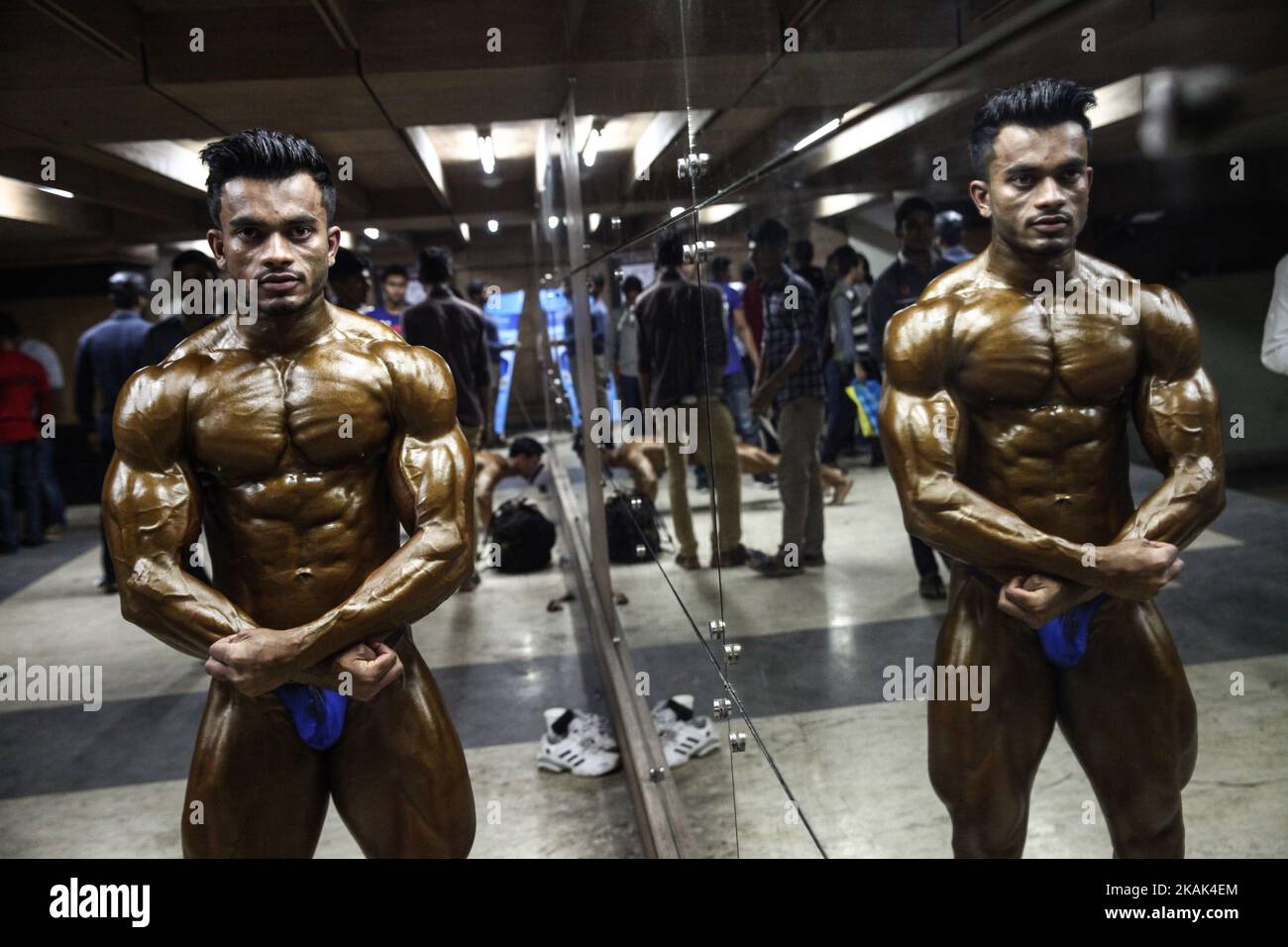 a bodybuilder poses with his winning trophy in Mr, in Dhaka, Bangladesh ...