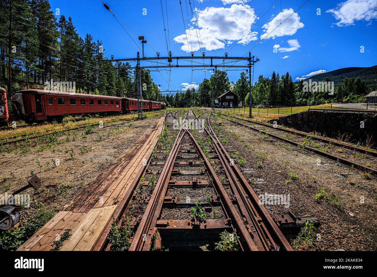A railway in the countryside with a red train on the side Stock Photo ...