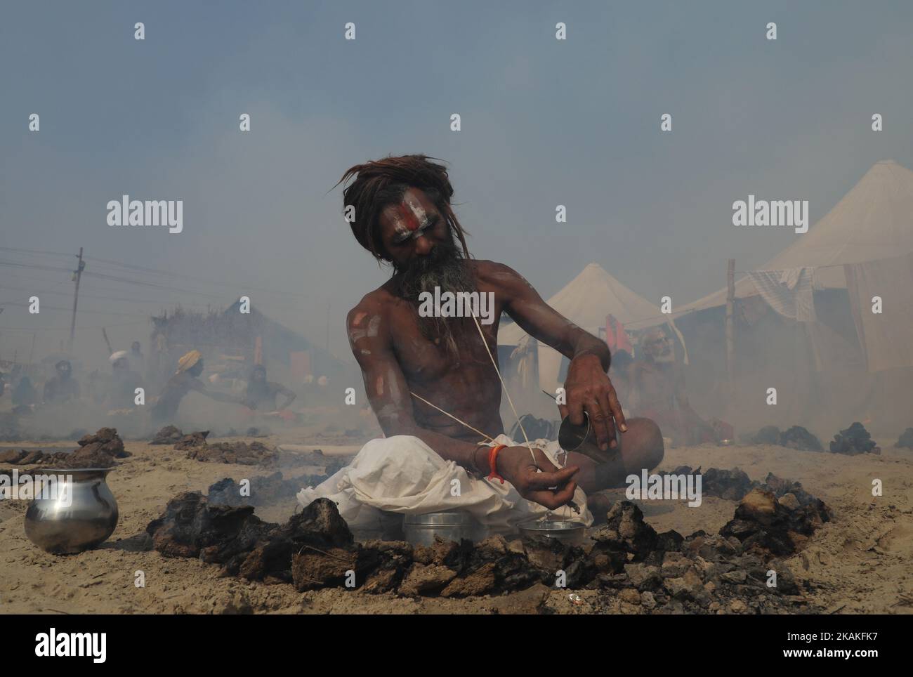 An Indian saint performs a ritual by burning dried cow dung cakesin a ...