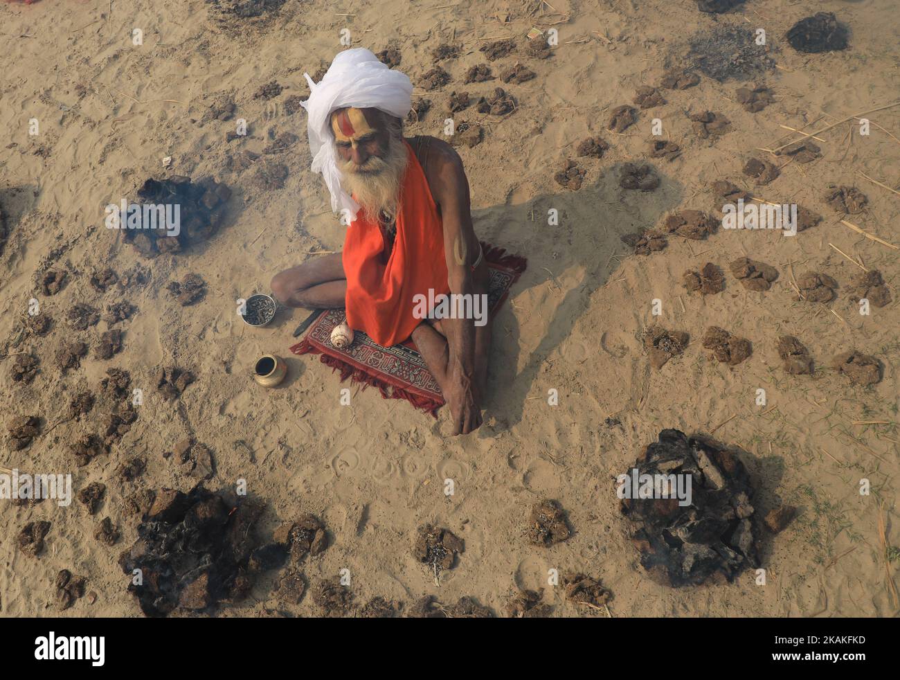 An Indian saint performs a ritual by burning dried cow dung cakesin a ...