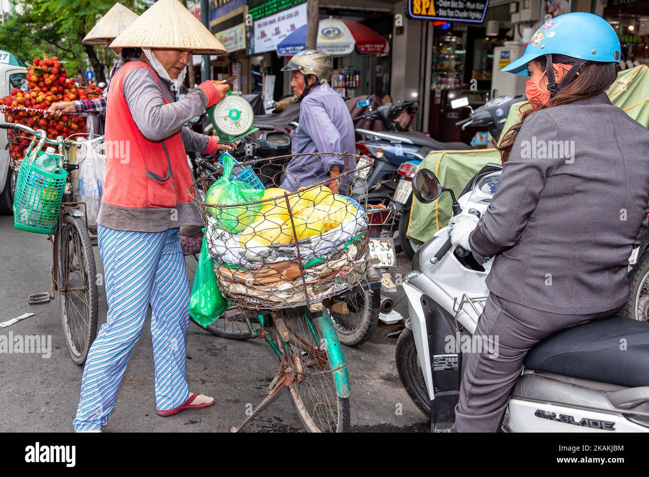 Street hawker wearing bamboo hat selling fruit to motorbike rider at ...