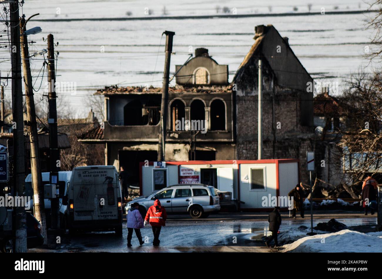 People are waking in front of a destroyed house and a van, near the ...