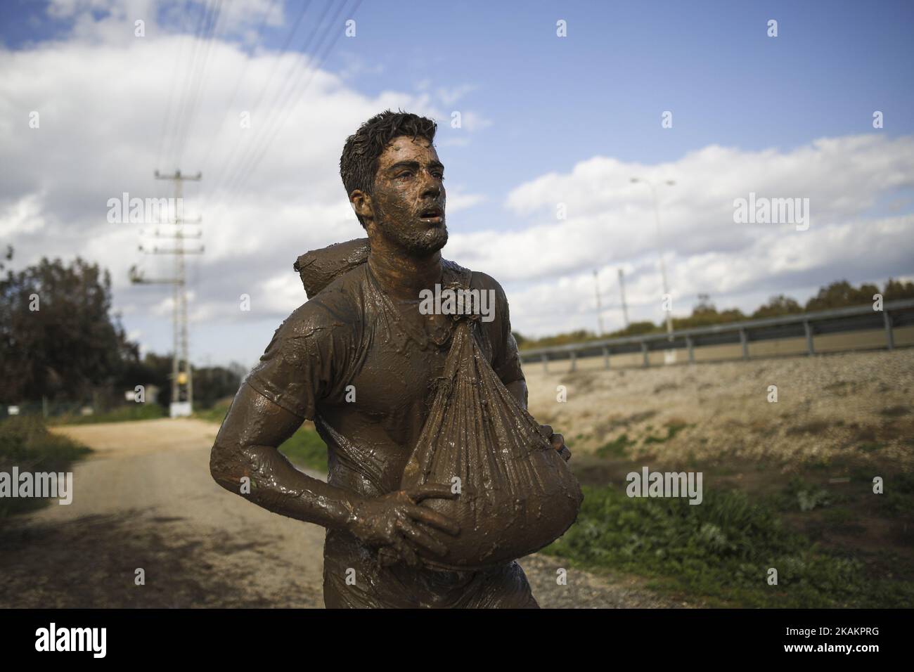 An Israeli carries heavy sandbags after crawling through mud during an ...