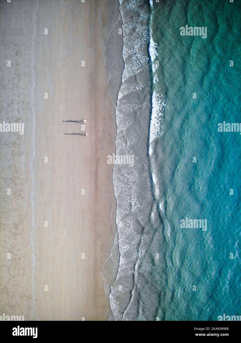 A vertical top shot of the pure ocean water washing the sandy coast ...