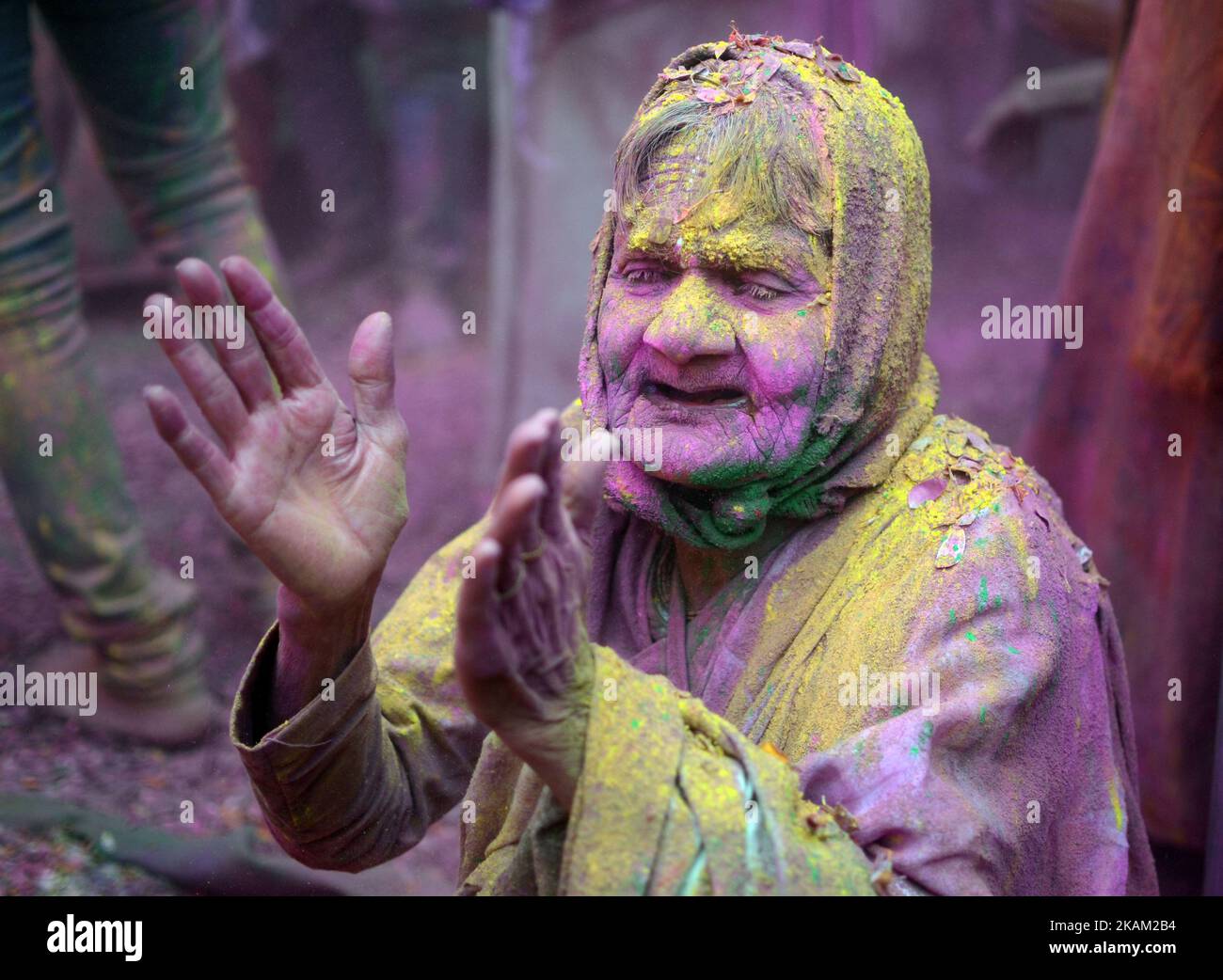 An indian Widow covered with colored powder and flower petels dance as ...