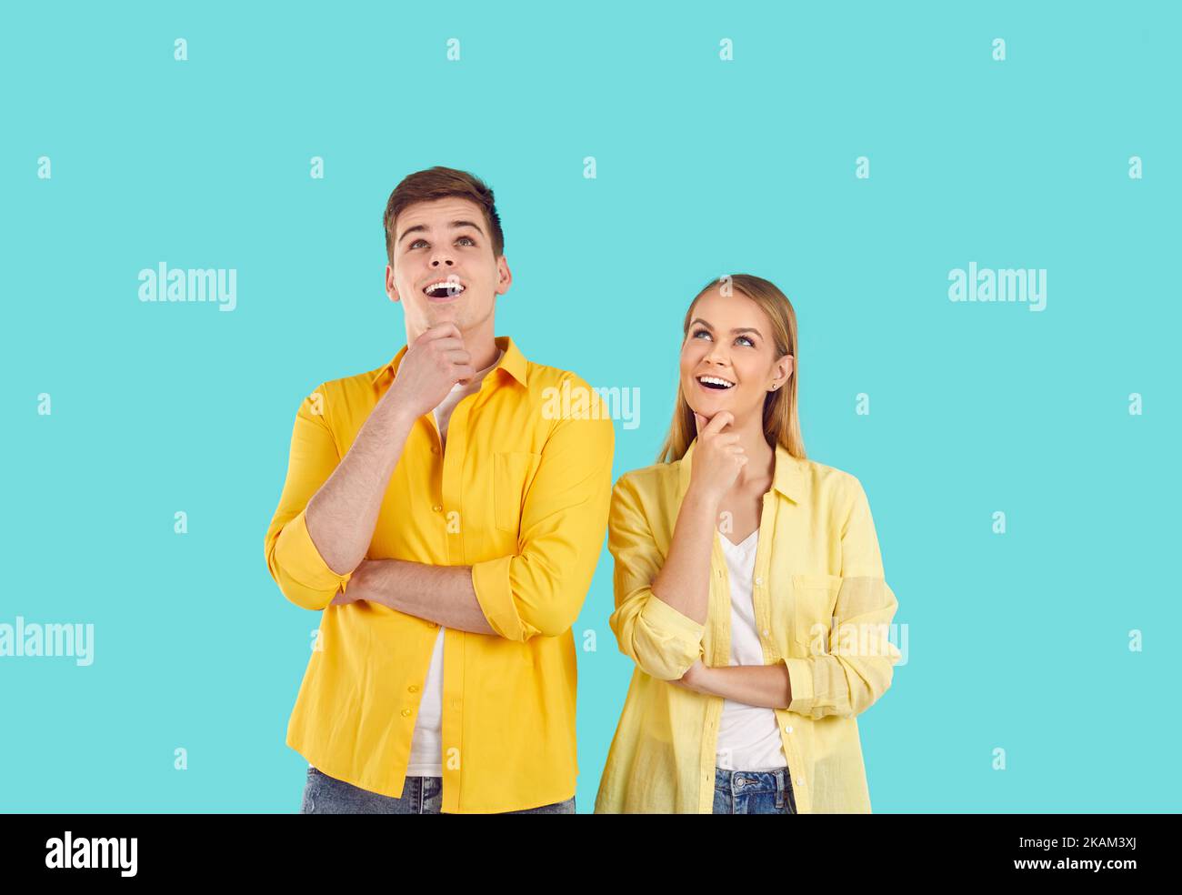 Happy young couple looking up and smiling while thinking about their ...