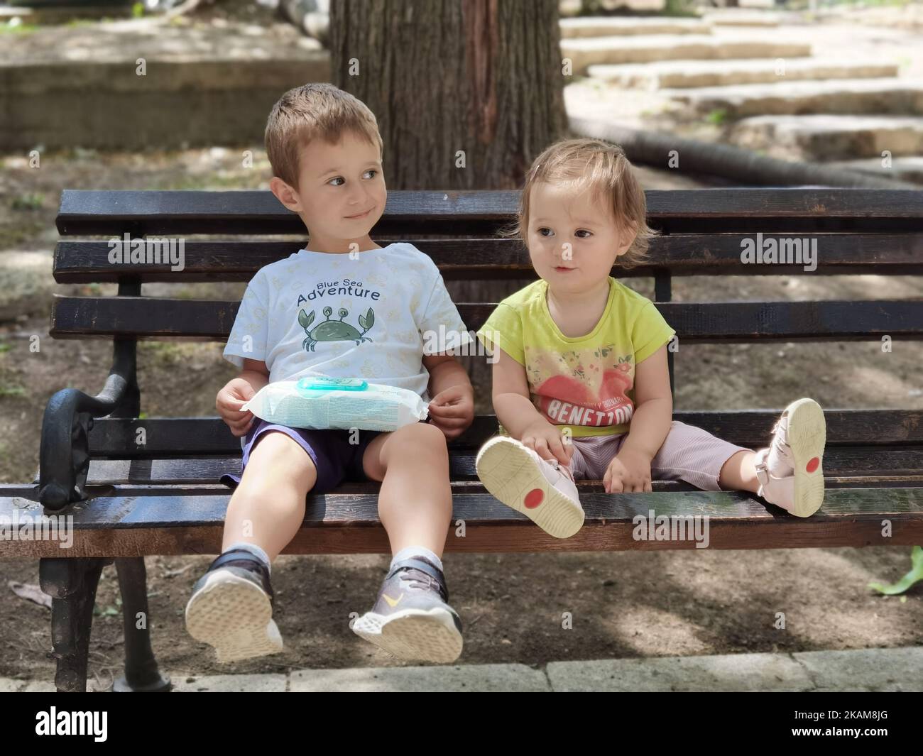 Two kids sitting on a bench hi-res stock photography and images - Alamy