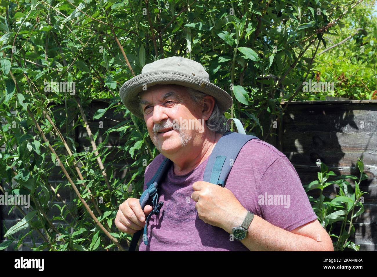 Elderly or senior man walking. Wearing a hat and a rucksack on his back ...