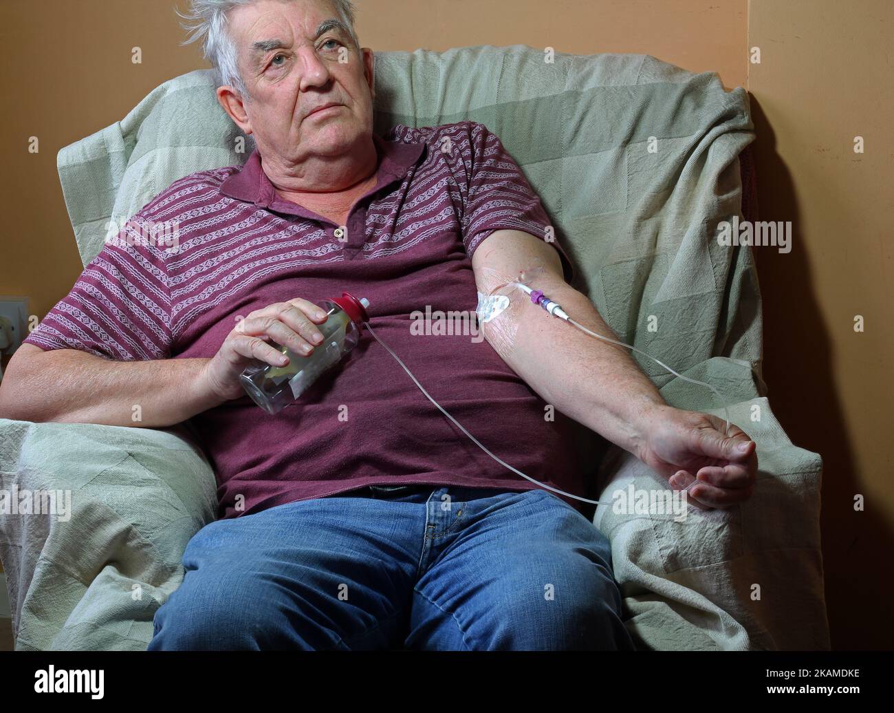 Senior or elderly man sitting in a chair at home and receiving ...