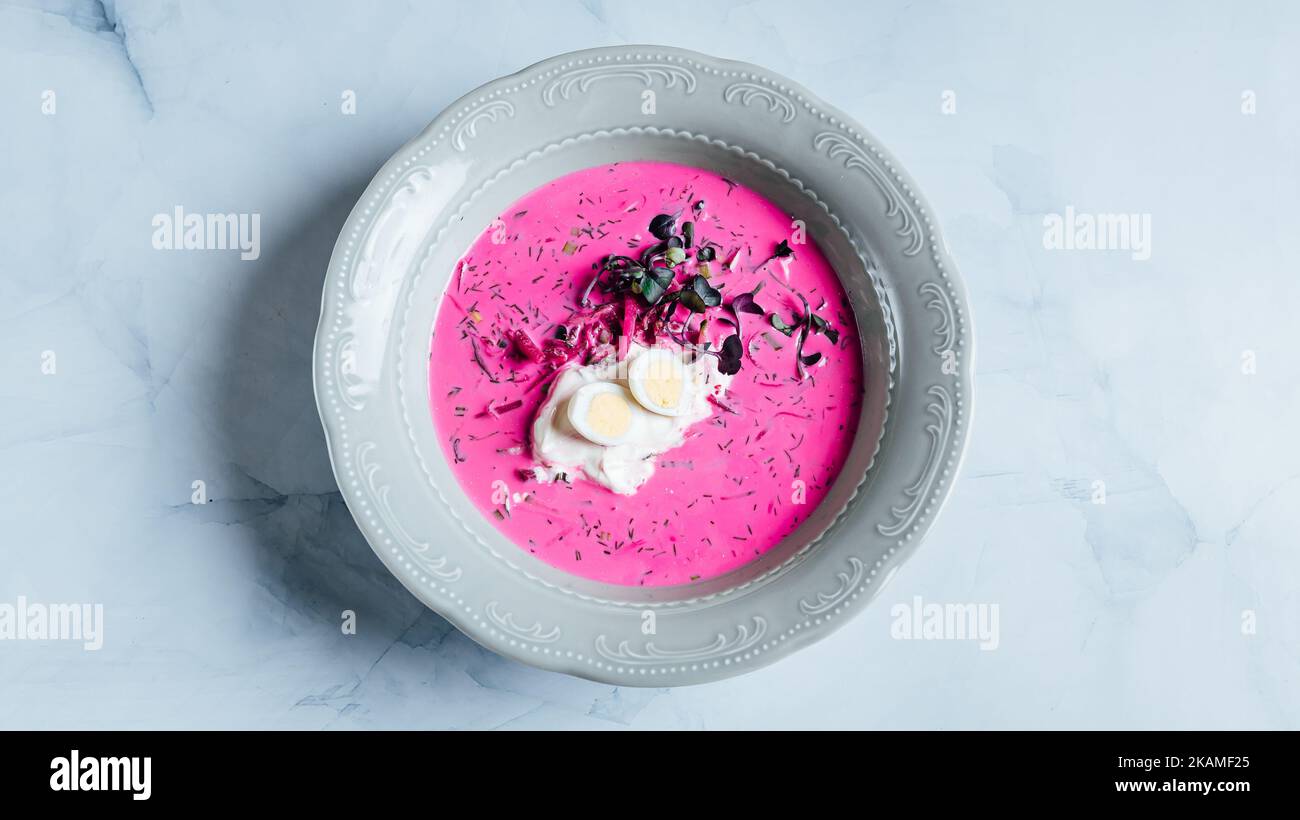A top view of a delicious pink creamy beetroot soup with sliced eggs in ...