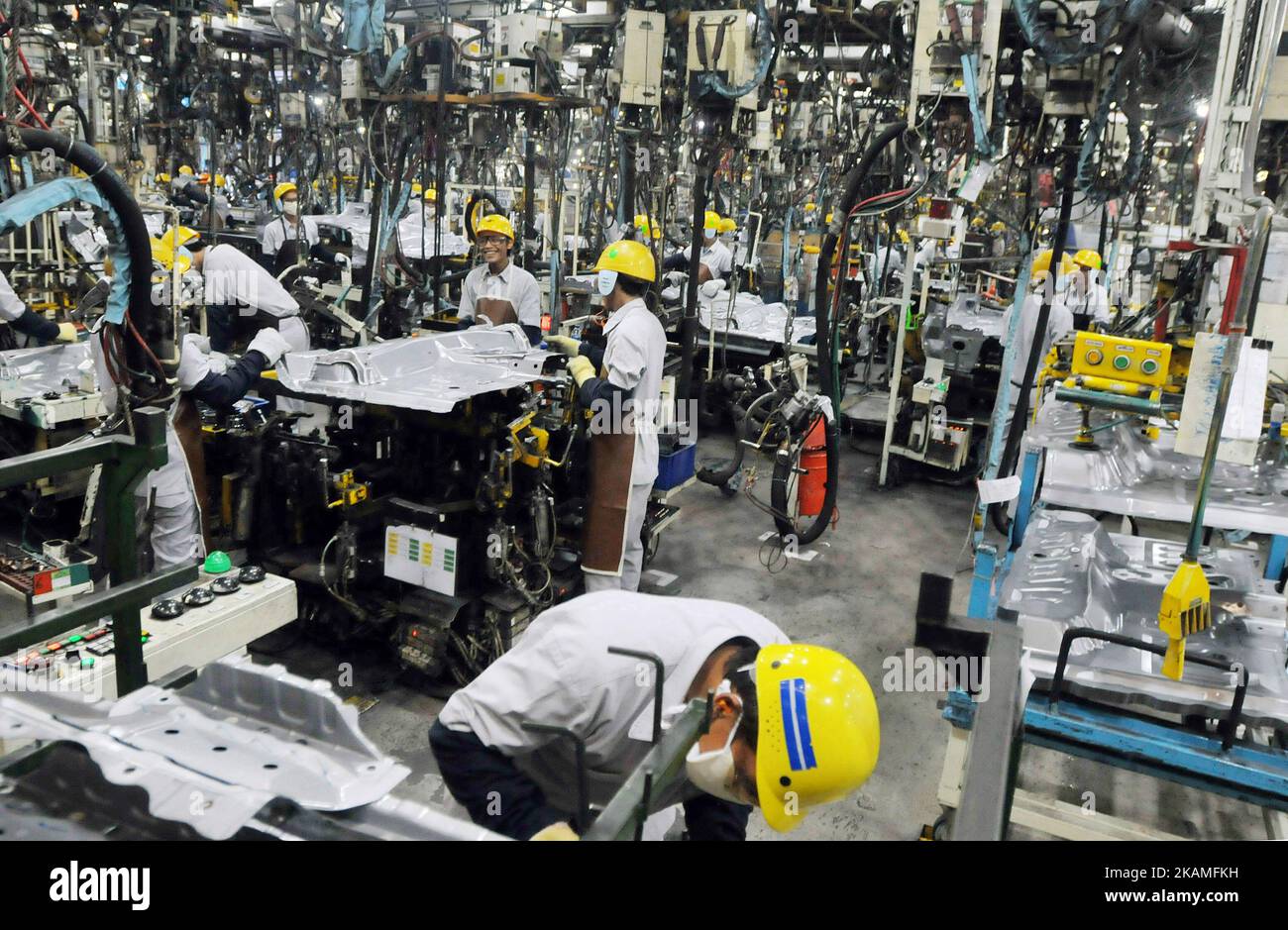 Workers connect components to be a car body plate at Toyota Motor ...