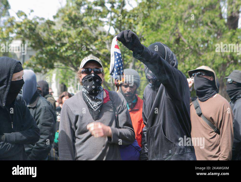 An anti-fascist lights an American flag on fire during a free speech ...