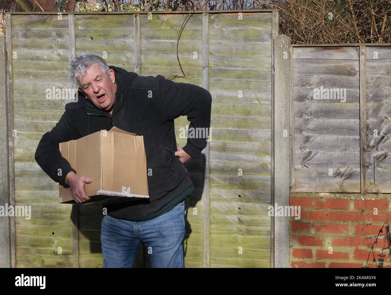 Old or elderly man lifting a heavy box and hurting himself. Box too ...