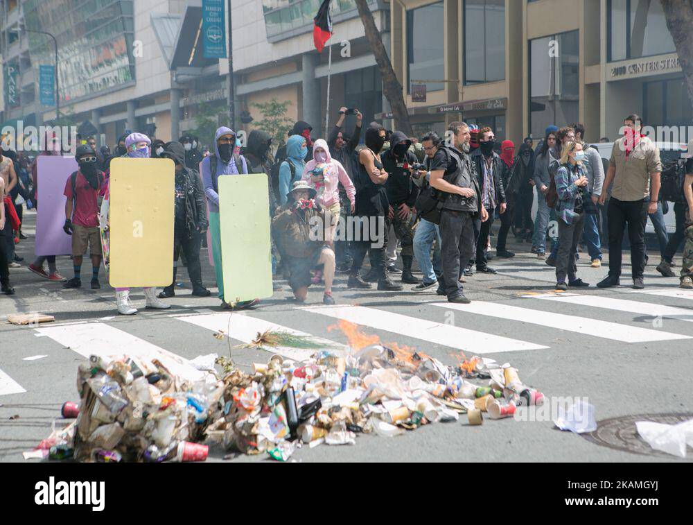 Protesters stand behind a trash fire set by anti-fascists during a free ...
