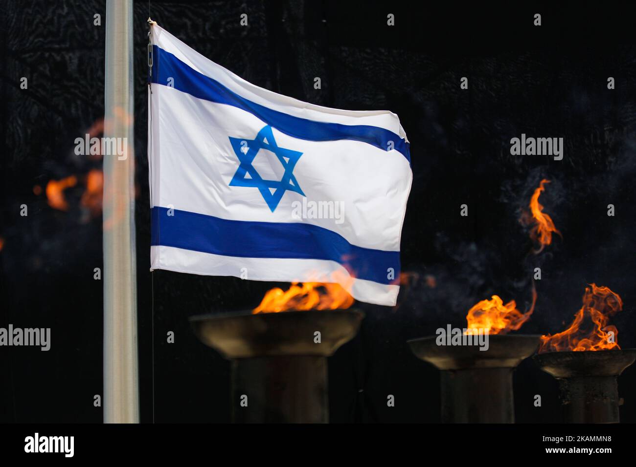 An Israeli flag behind torches is seen during the annual Holocaust ...