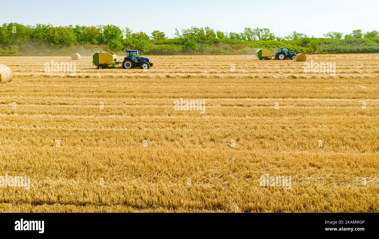 Above view on tractor as pulling round baler, machine that rolls up the ...