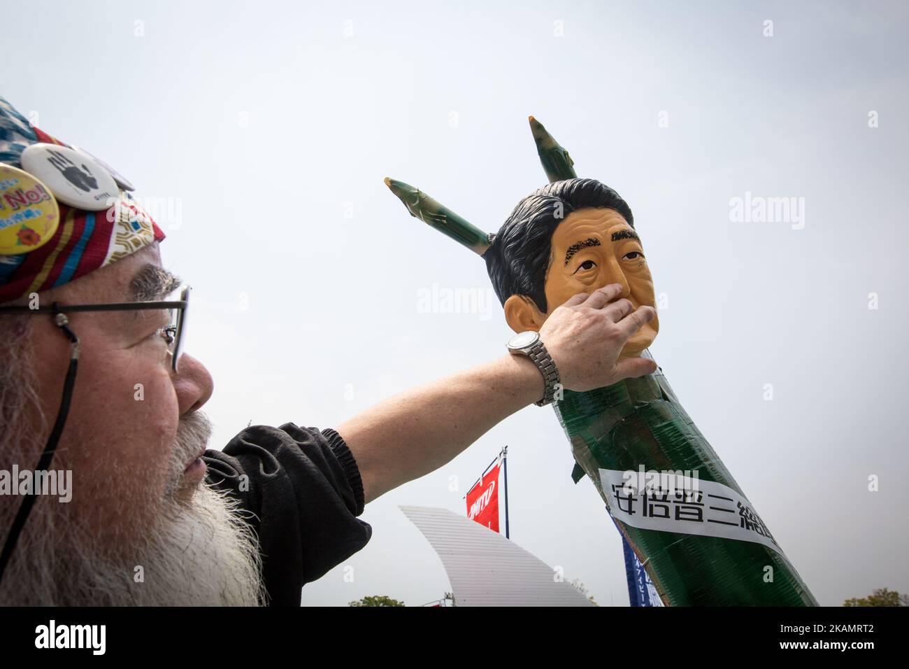 An angry demonstrator covers the mouth on an effigy of Japanese PM ...