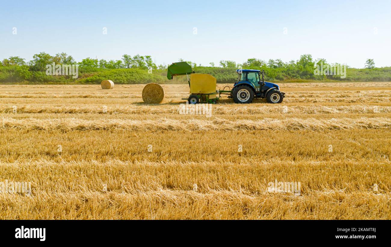 Above view on tractor as pulling round baler, machine that rolls up the ...