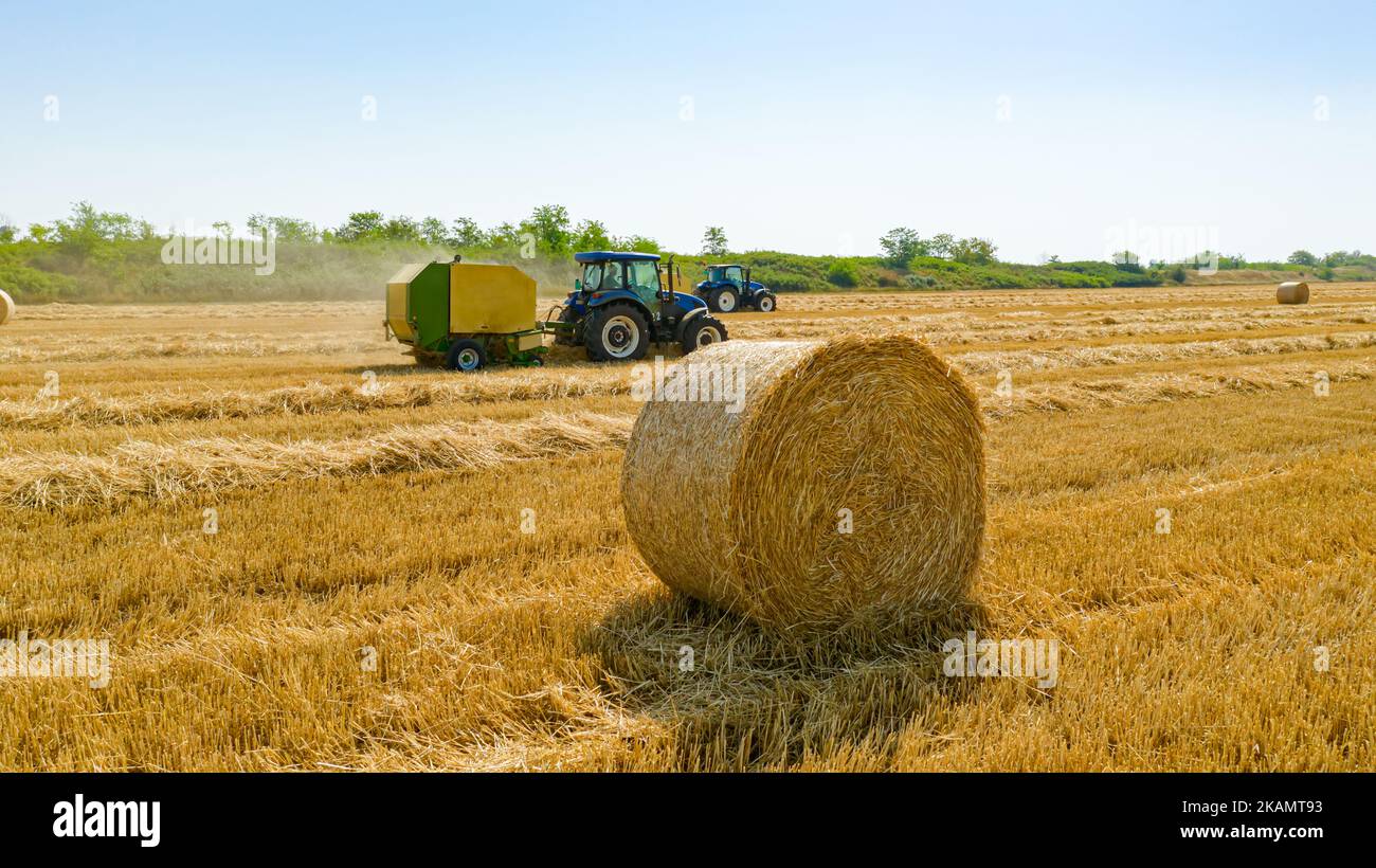 Above view round bale of straw after harvest, in background tractor is ...