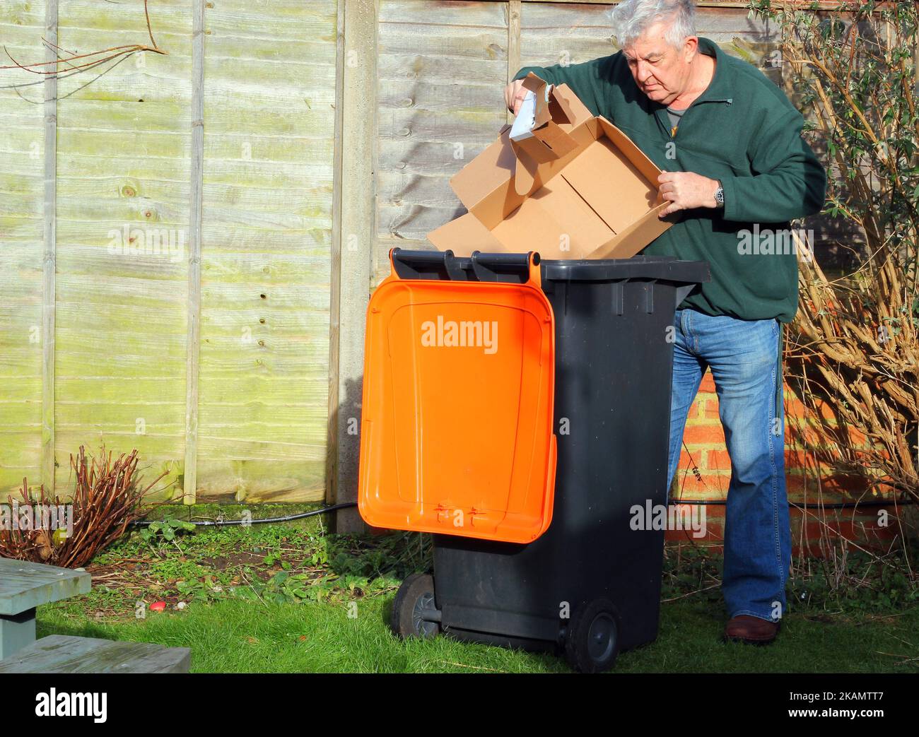 senior or elderly man placing cardboard into a recycling bin. Filling a ...