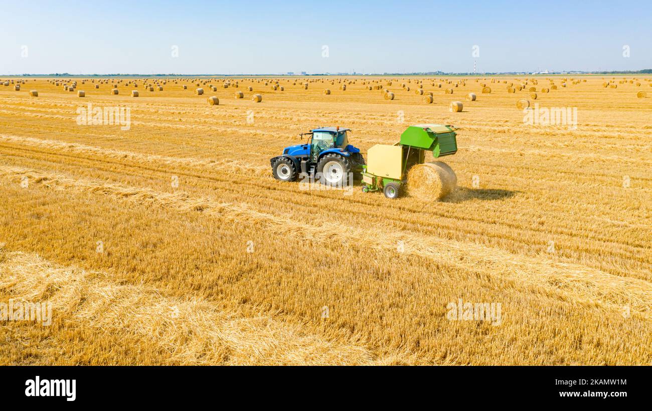 Above view on tractor as pulling round baler, machine that rolls up the ...