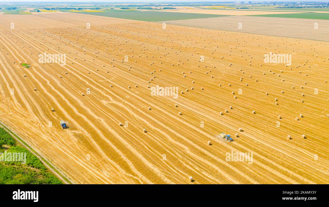 Above view on tractor as pulling round baler, machine that rolls up the ...